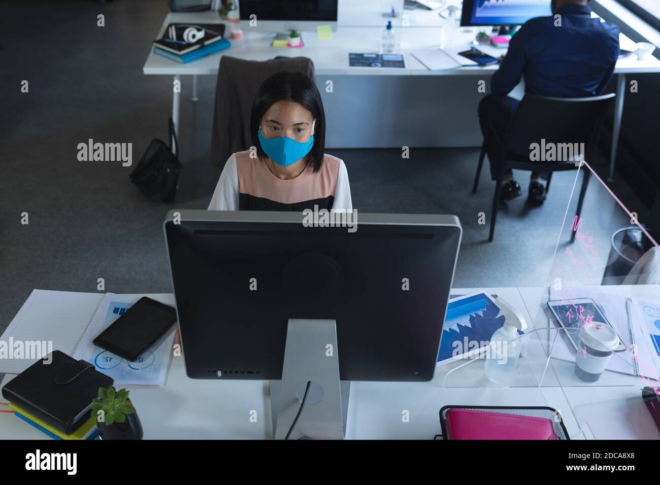 Overhead view of asian woman wearing face mask using computer while ...