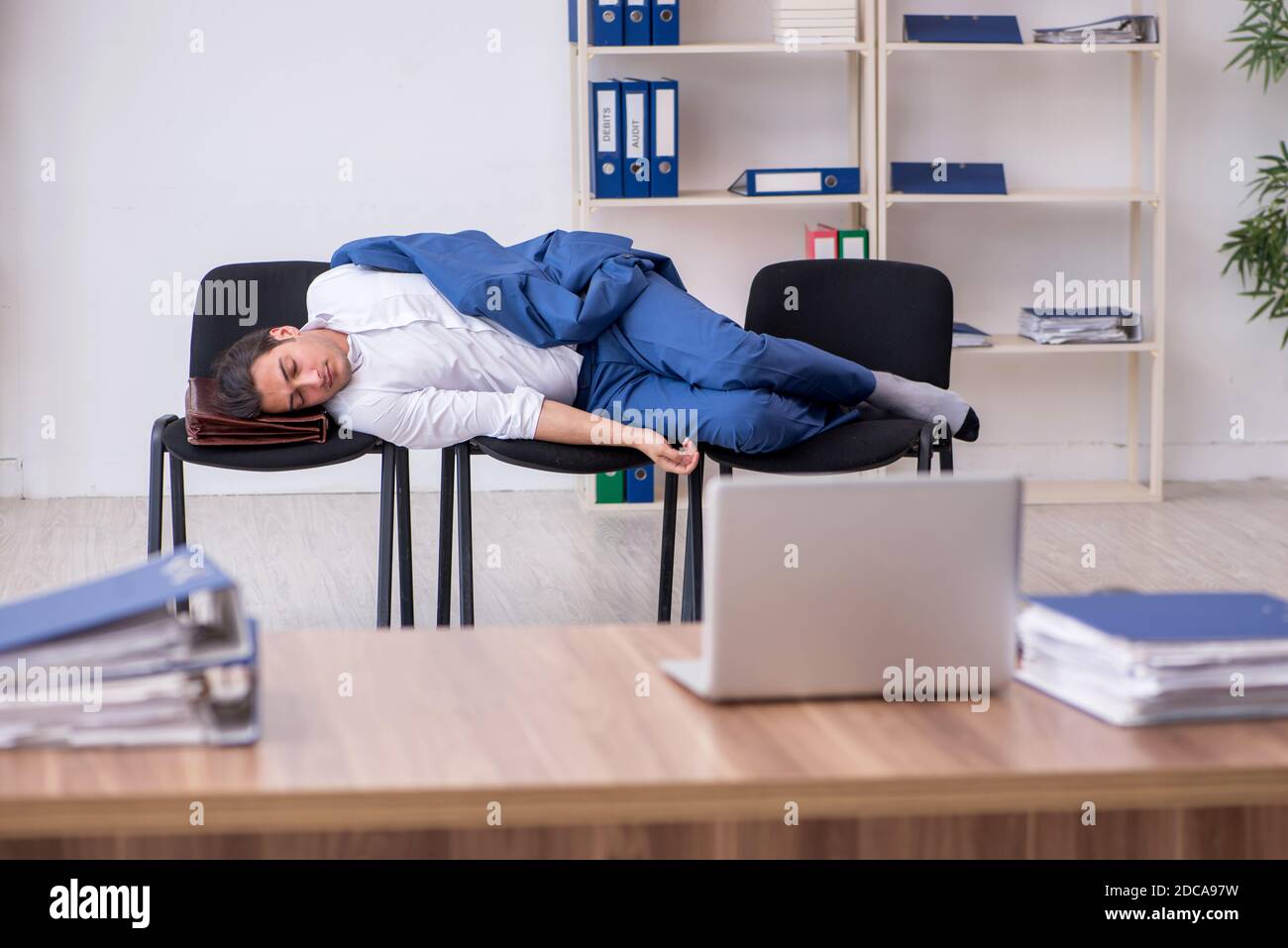 Young employee sleeping in the office on chairs Stock Photo - Alamy