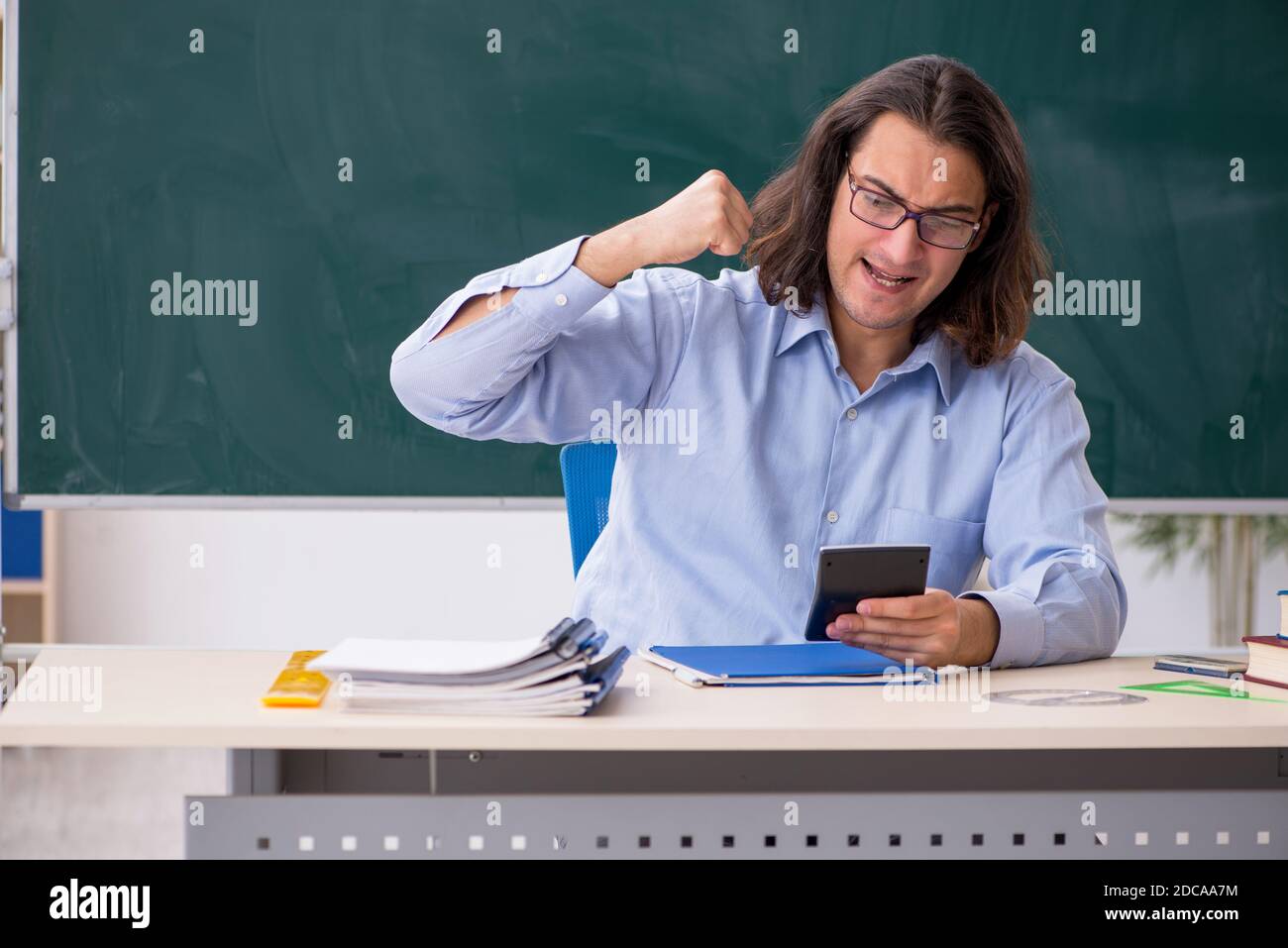 Young teacher in front of green board Stock Photo - Alamy