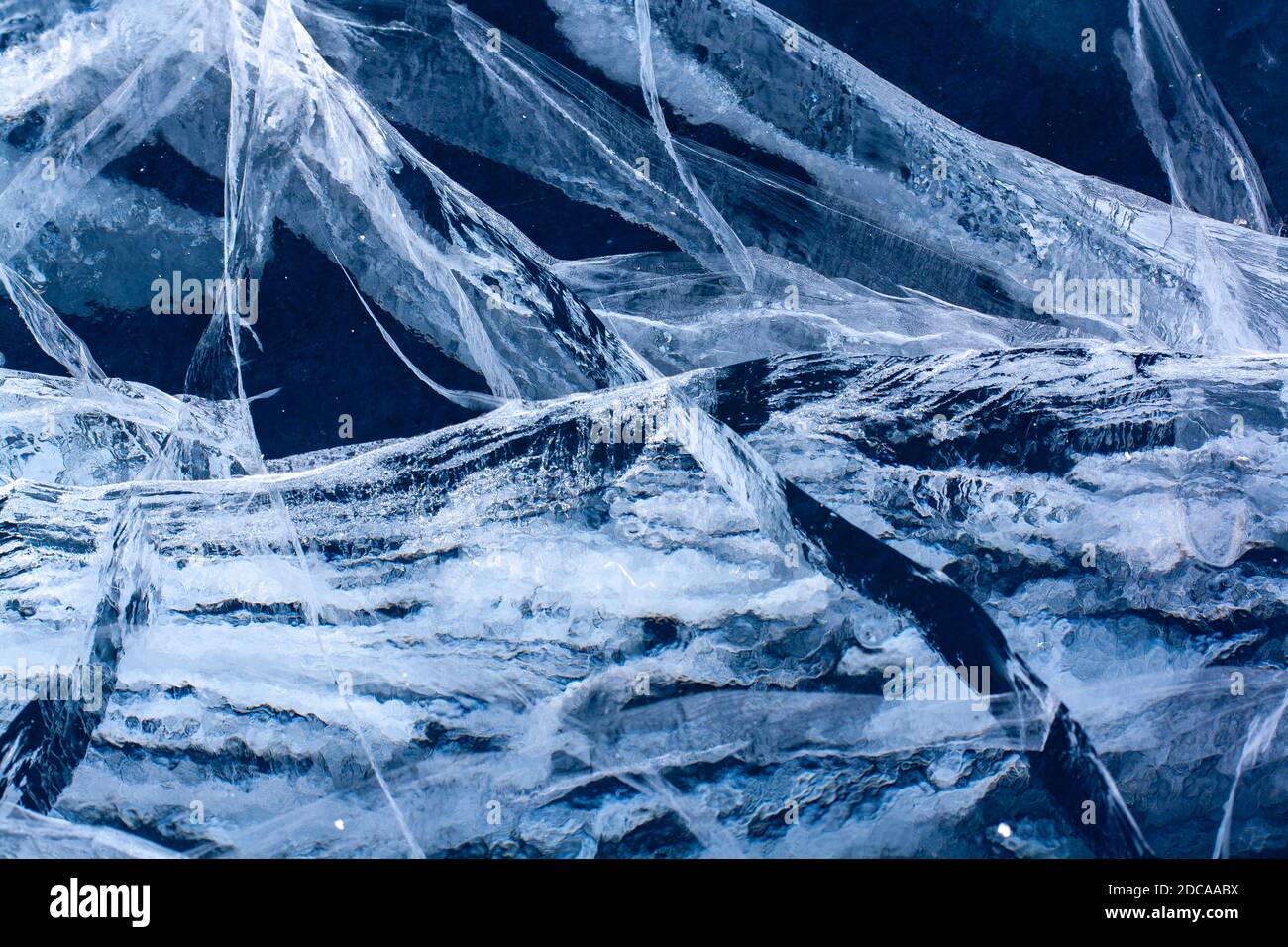 Large deep cracks in the ice of the lake. Blue thick and transparent ...