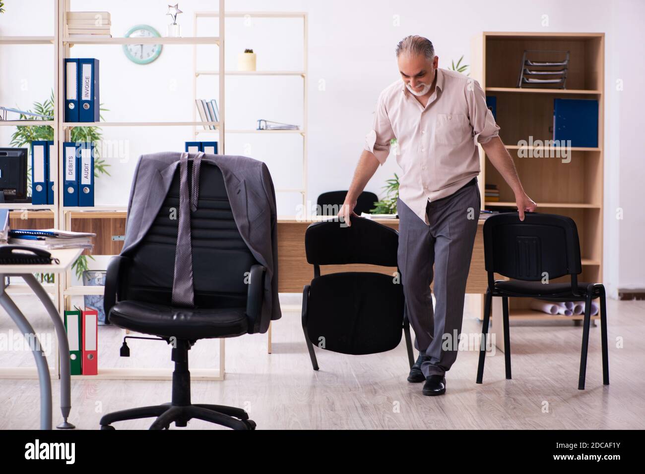 Senior male employee doing physical exercises at workplace Stock Photo ...