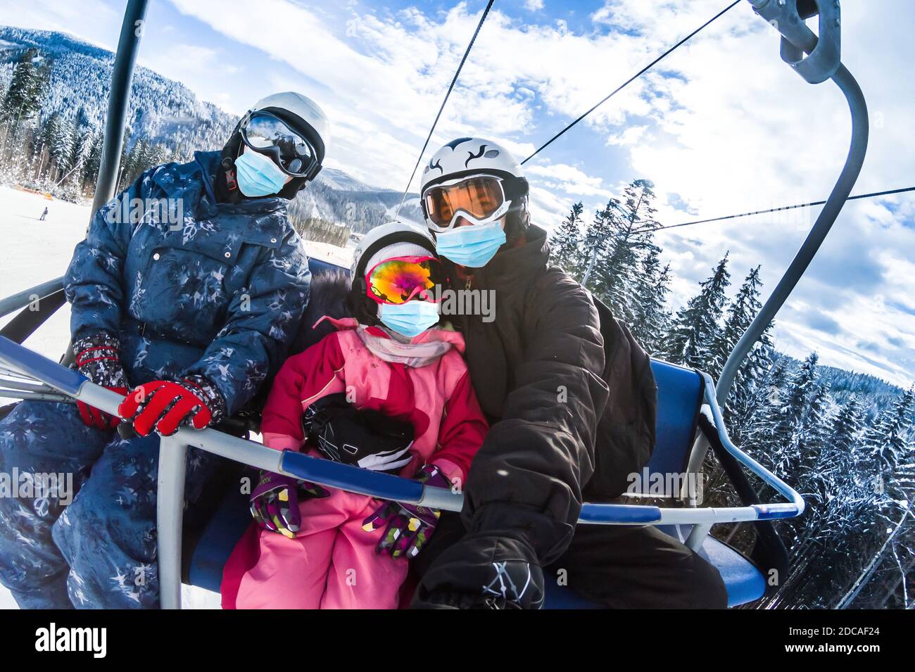 family wearing a medical mask during COVID-19 coronavirus on a snowy ...