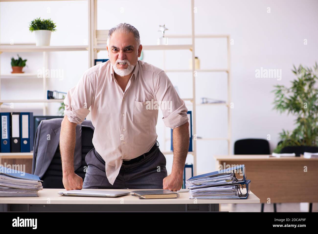 Senior male employee doing physical exercises at workplace Stock Photo ...