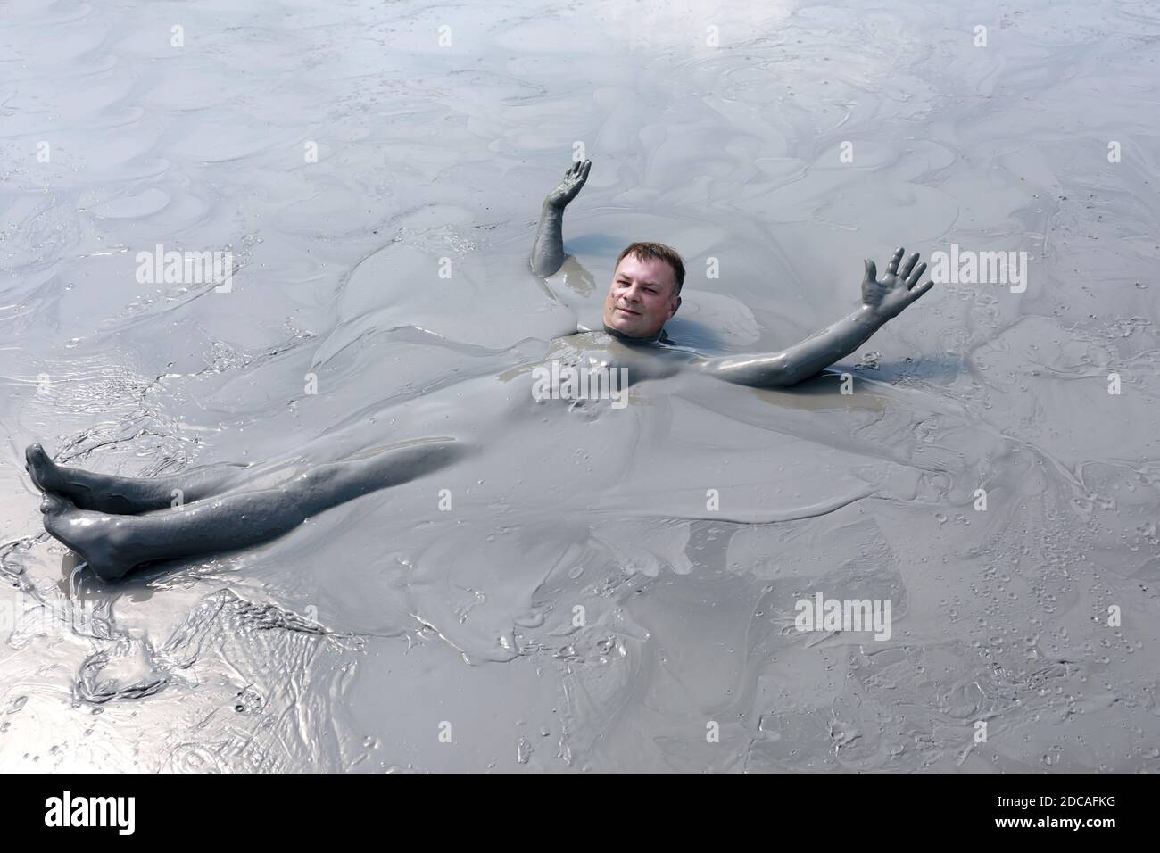 Portrait of man relaxing in mud pool Stock Photo - Alamy