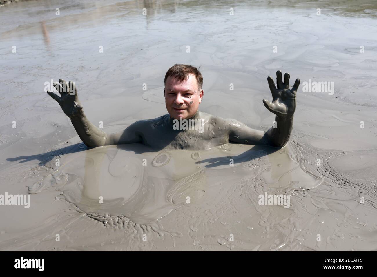 Portrait of man standing in mud pool Stock Photo - Alamy