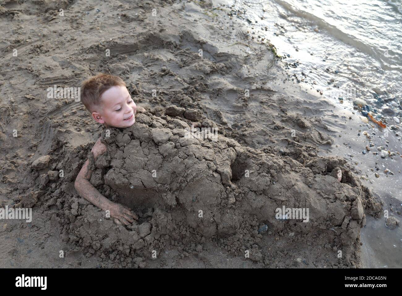 Boy buried in sand on hi-res stock photography and images - Alamy