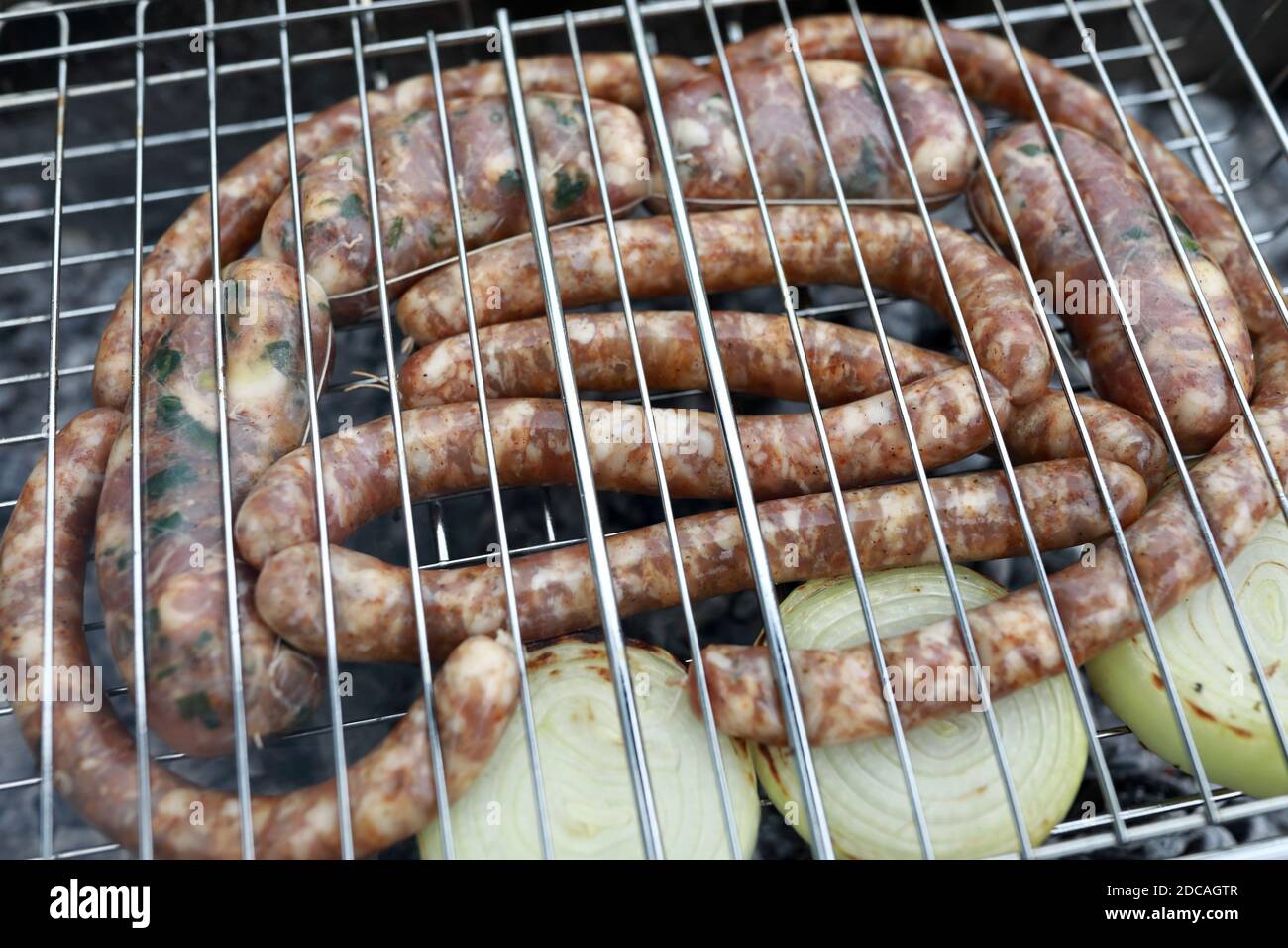 Cooking sausages and onion rings on grill Stock Photo - Alamy