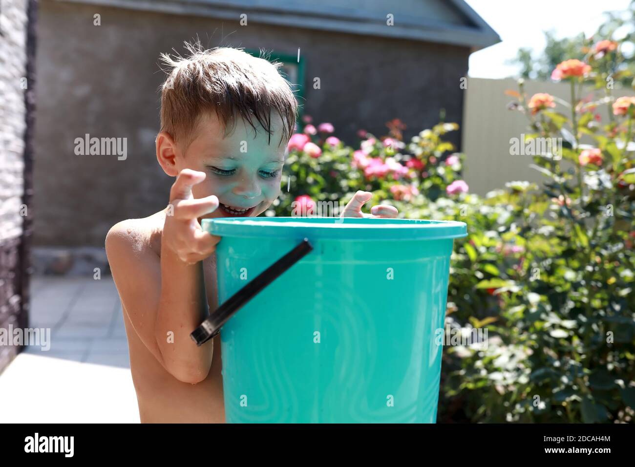 Boy catches drops of water with bucket in backyard Stock Photo - Alamy