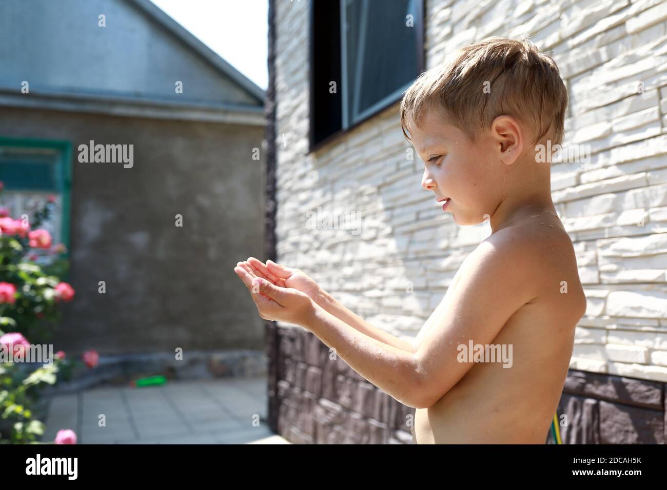 Boy catches drops of water with his hands in backyard Stock Photo - Alamy