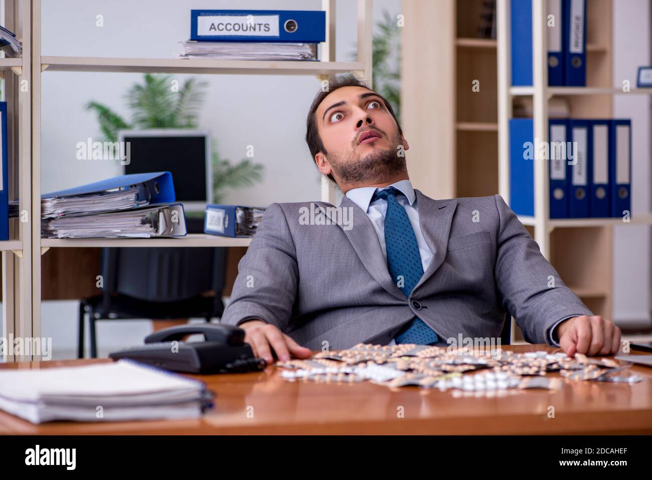 Male sick employee suffering at workplace Stock Photo - Alamy