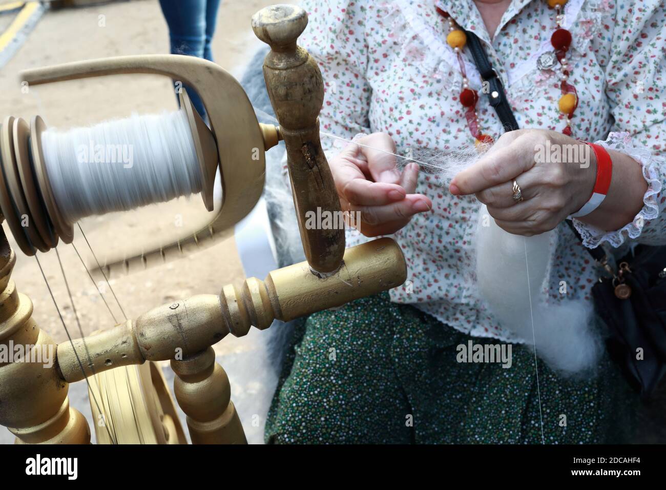 Woman spins thread of wool on spinning wheel Stock Photo - Alamy