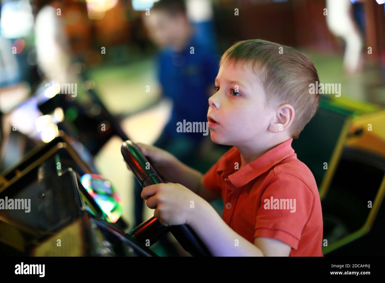 Child playing car simulator in amusement center Stock Photo - Alamy