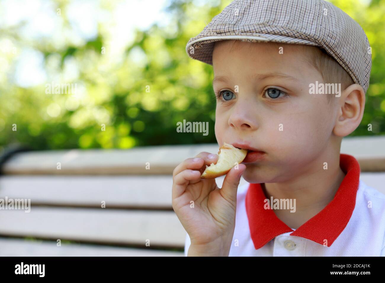 Child eating apple on bench in park Stock Photo - Alamy