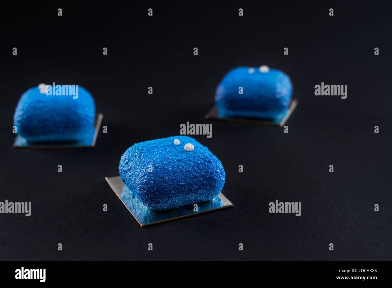 Three small matte cakes in row in restaurant isolated on black studio ...