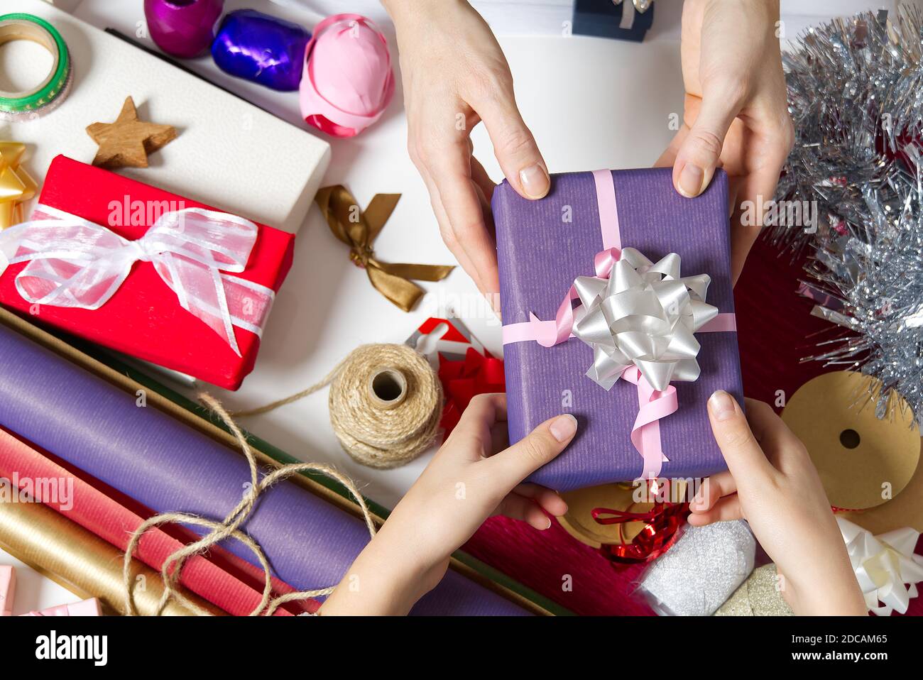 Female hands holding a small gift box wrapped in packing paper. To give ...