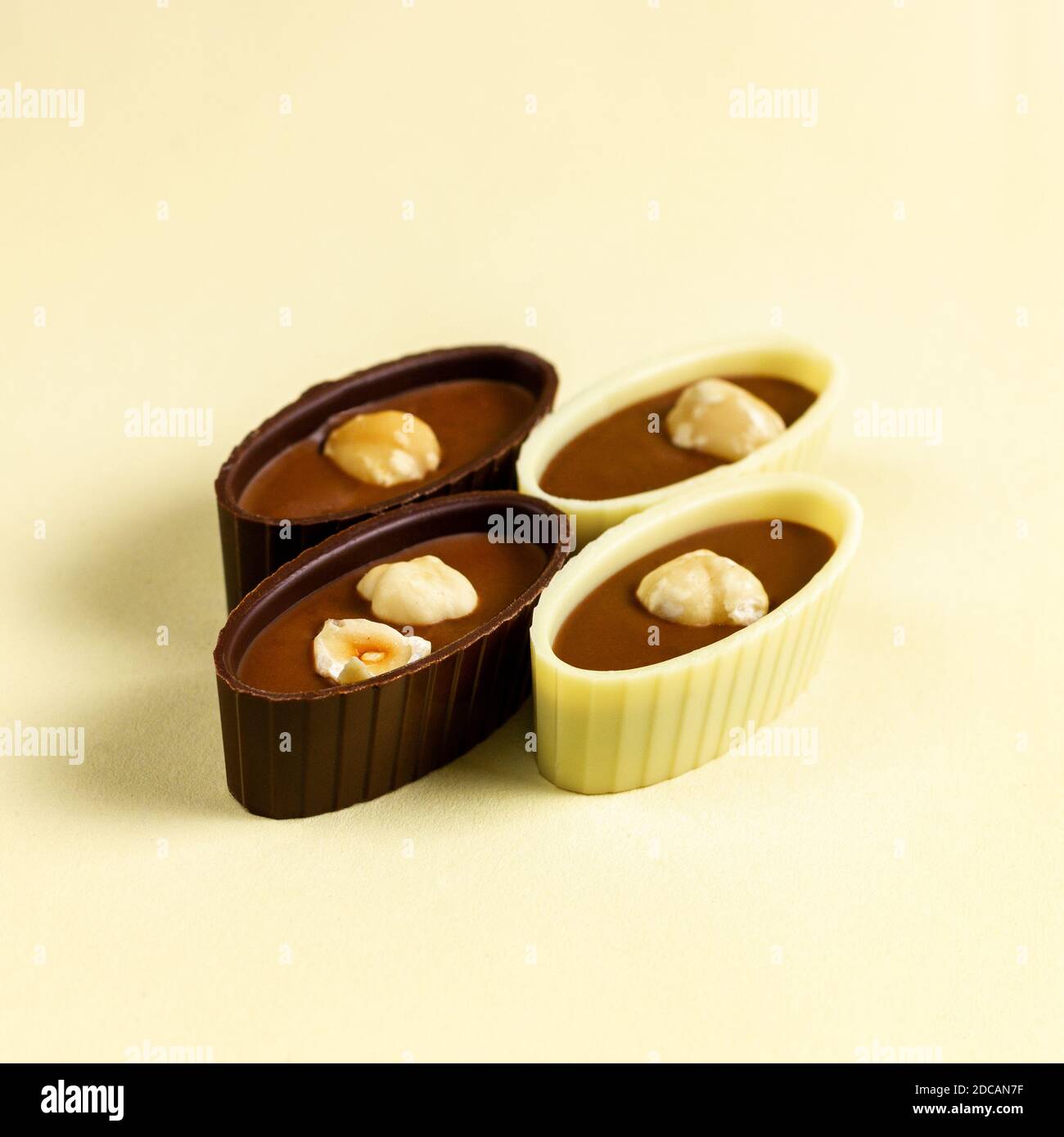 Four chocolates with nuts on a yellow background. White and dark ...