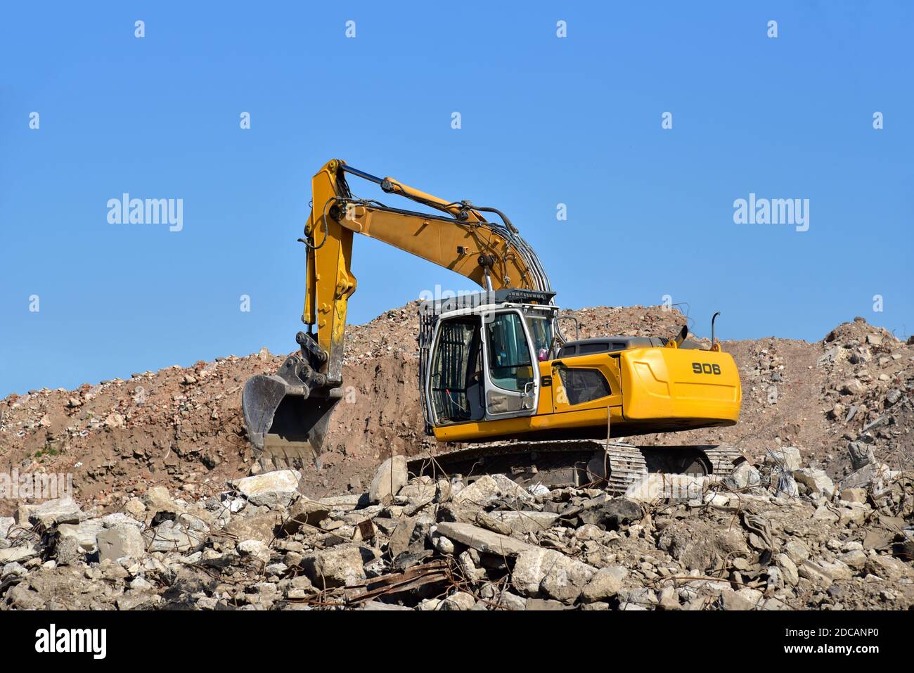 Yellow excavator at landfill for disposal of construction waste ...