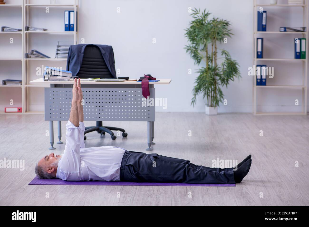 Aged employee doing physical exercises during break Stock Photo - Alamy