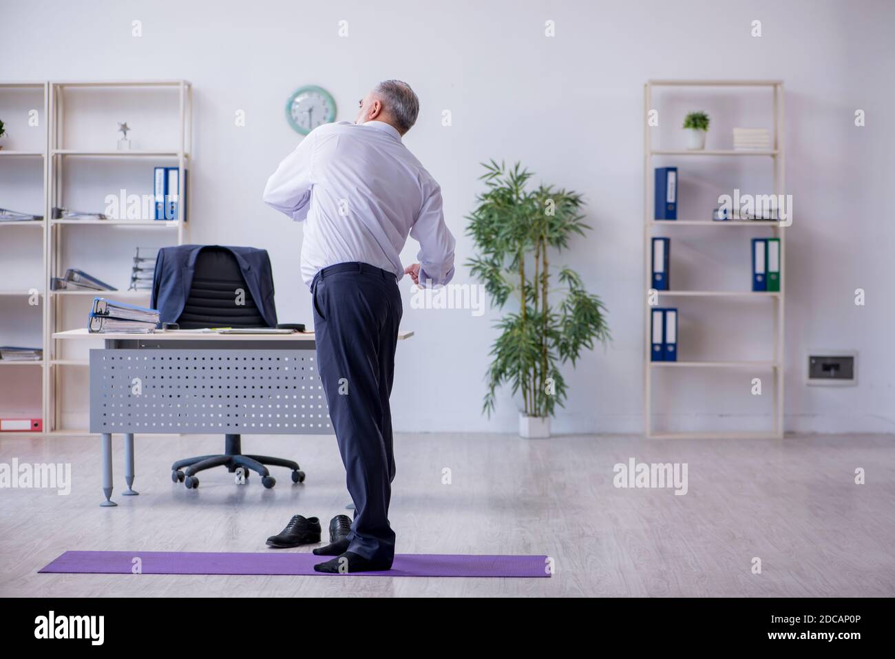 Aged employee doing physical exercises during break Stock Photo - Alamy