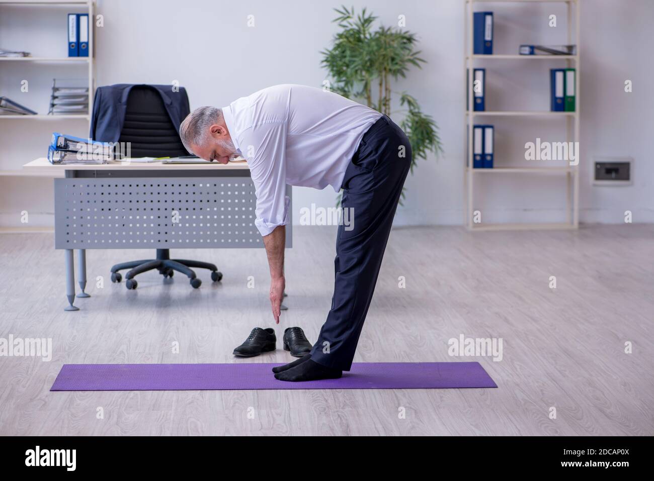 Aged employee doing physical exercises during break Stock Photo - Alamy