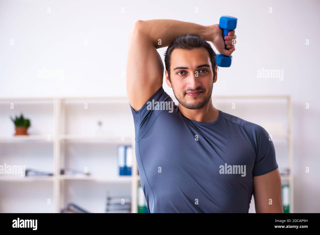 Young male employee doing sport exercises in the office Stock Photo - Alamy