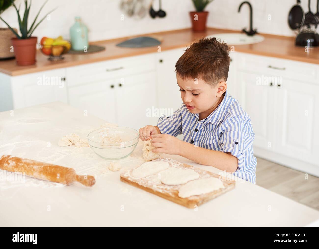 The boy sits at the kitchen table and sculpts something from the dough ...