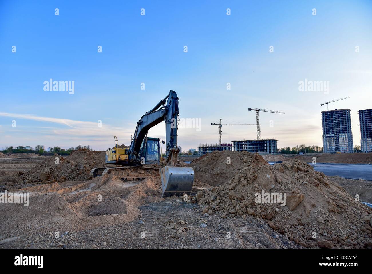 Excavator during earthmoving at construction site on sunset background ...