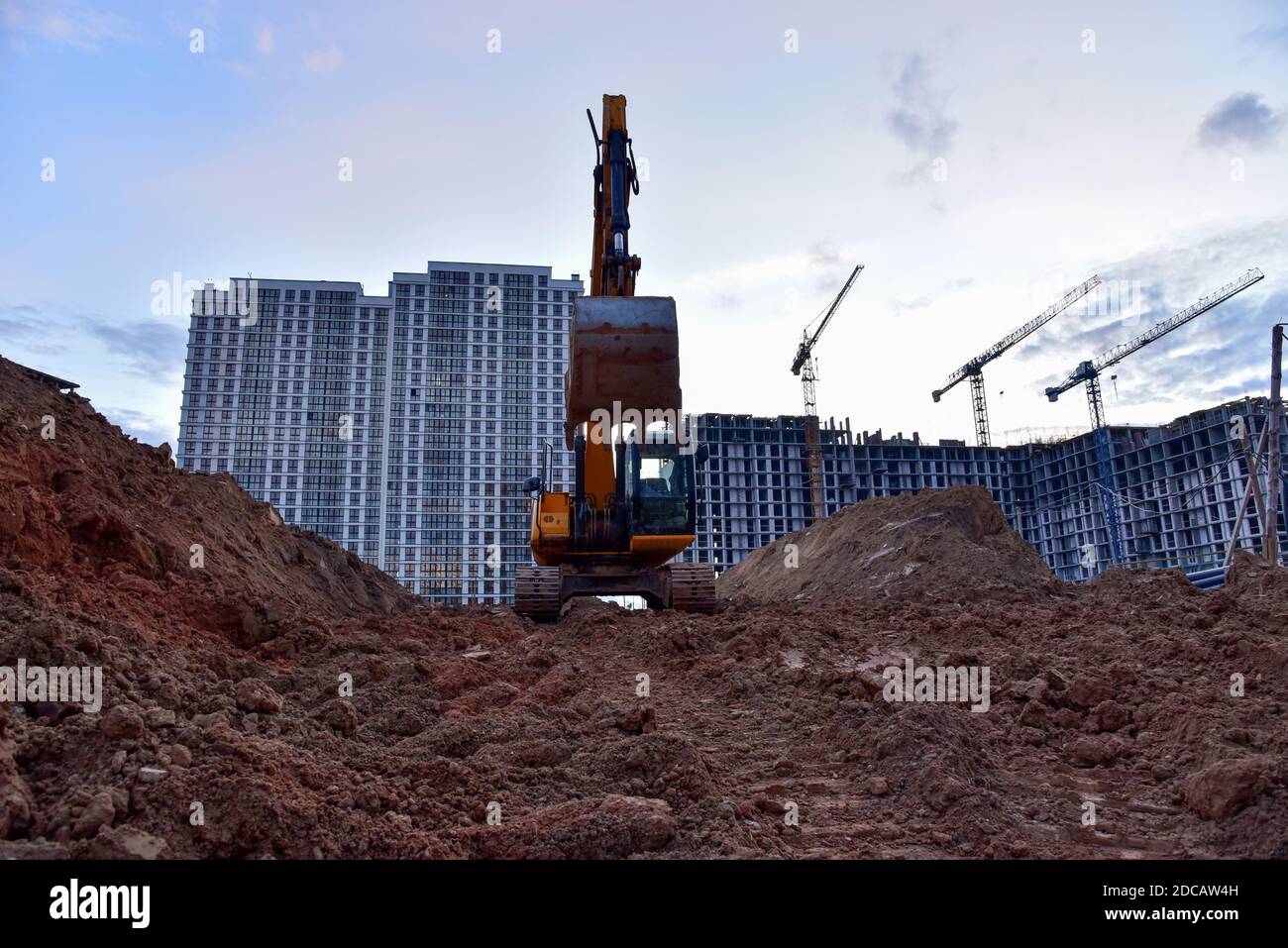 Excavator during earthmoving at construction site on sunset background ...