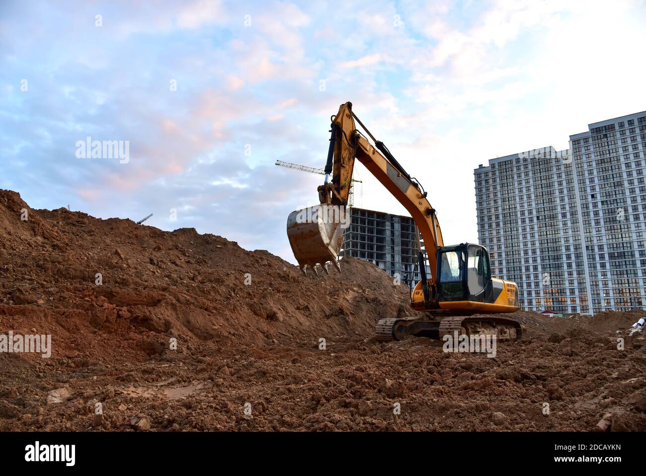 Excavator during earthmoving at construction site on sunset background ...