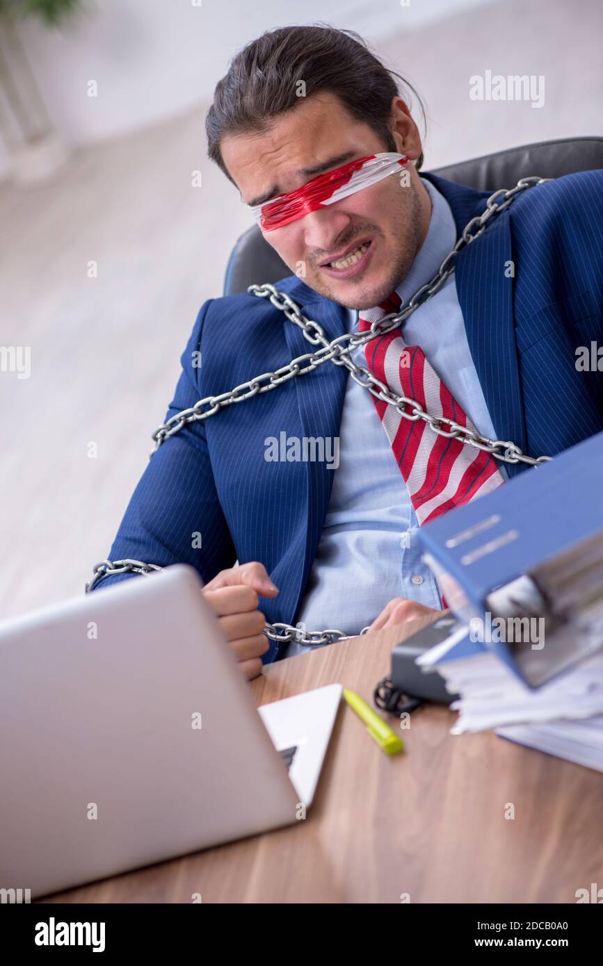 Chained employee unhappy with excessive work in the office Stock Photo ...