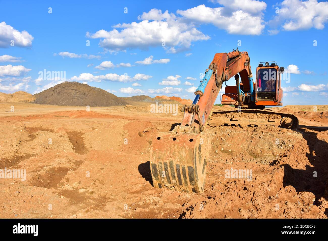 Excavator working on earthmoving at open pit mining on blue sky ...