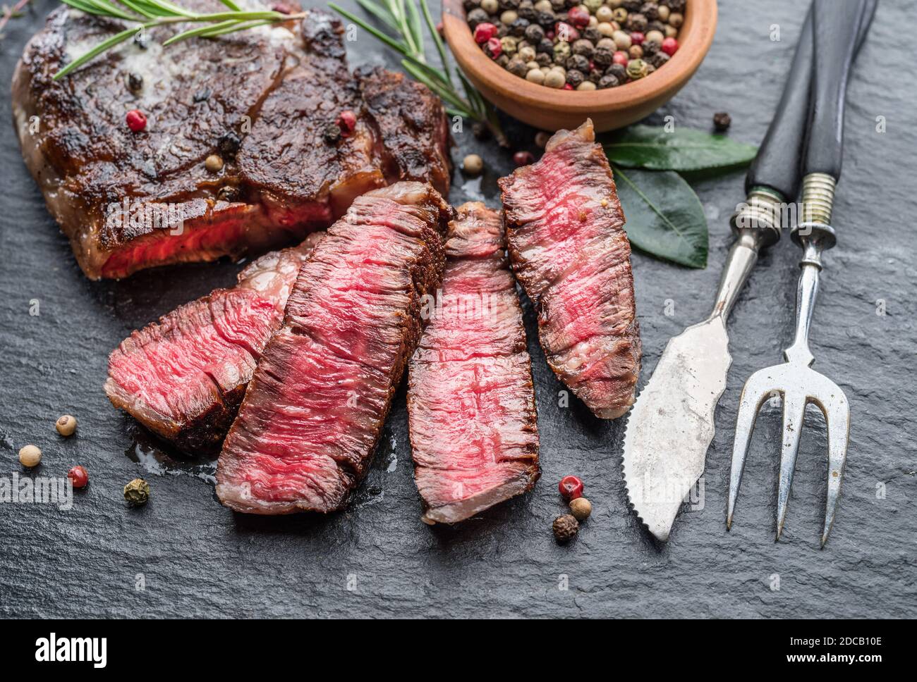 Medium rare Ribeye steak with herbs on graphite board Stock Photo - Alamy
