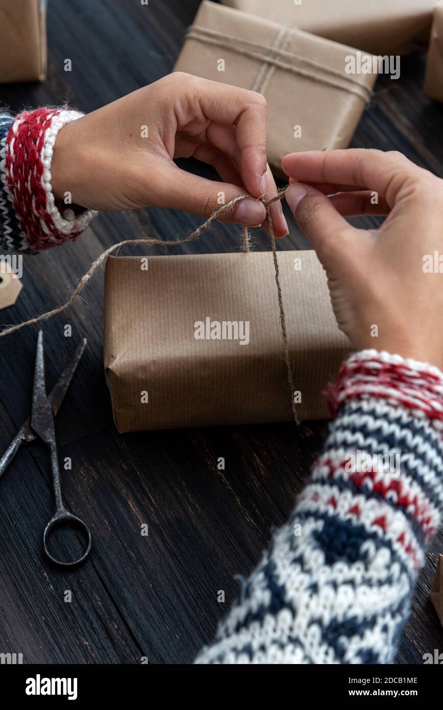 Female's hands in pullover enveloping Christmas gift box decorated with ...