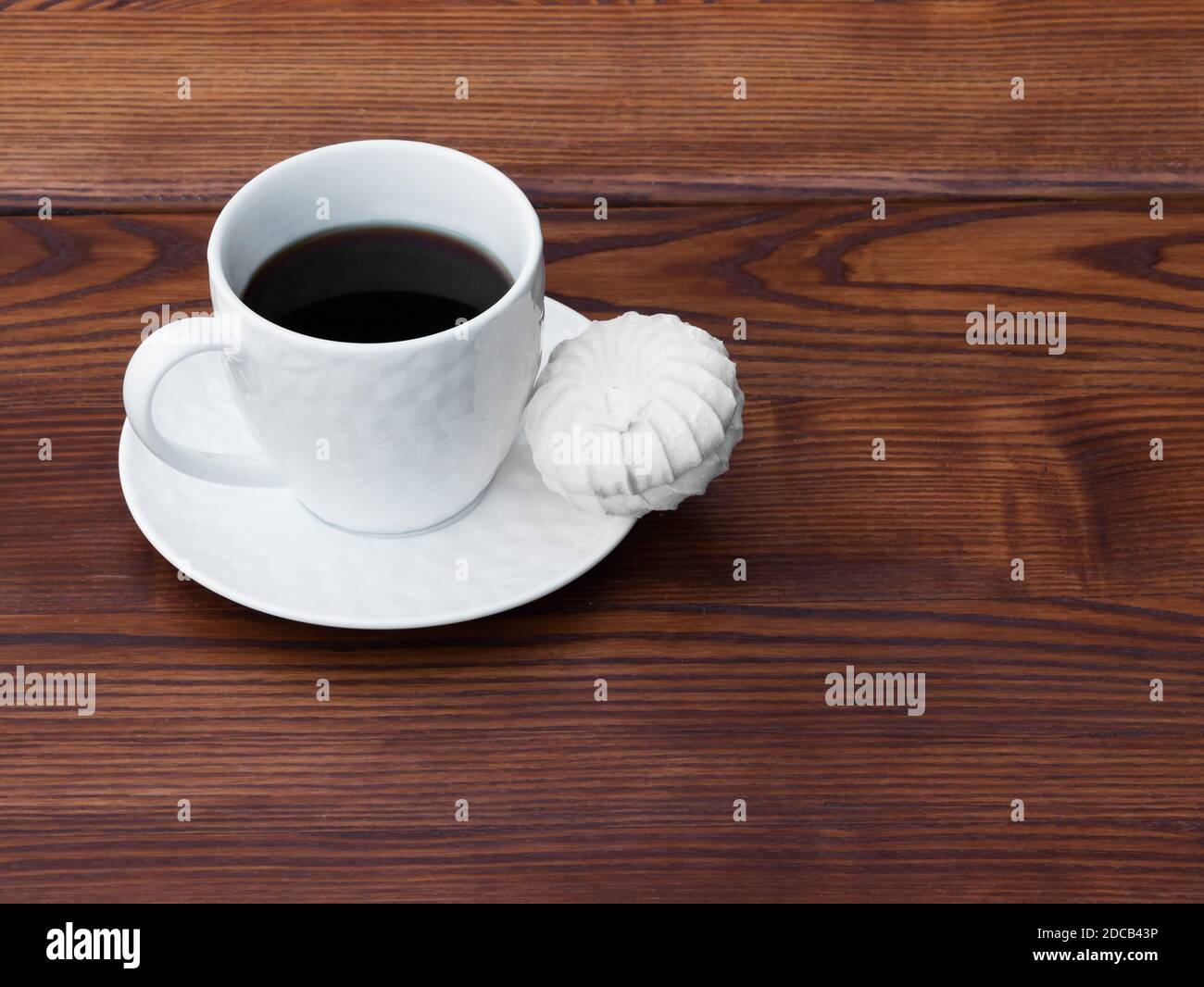 White cup of coffee and pink zefir on the wooden background ...