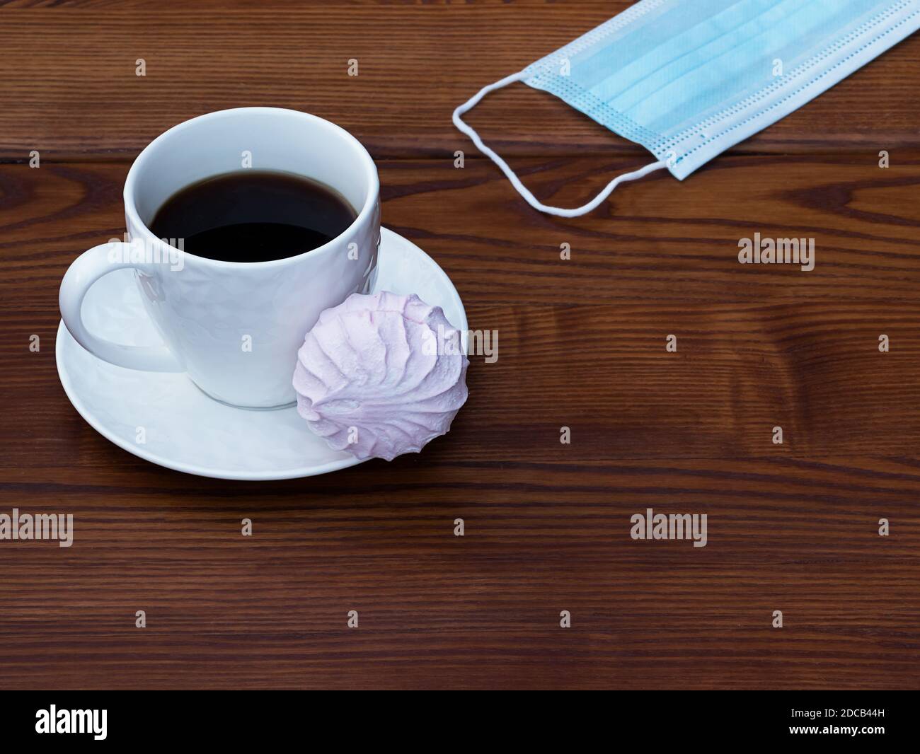 White cup of coffee and pink zefir on the wooden background ...