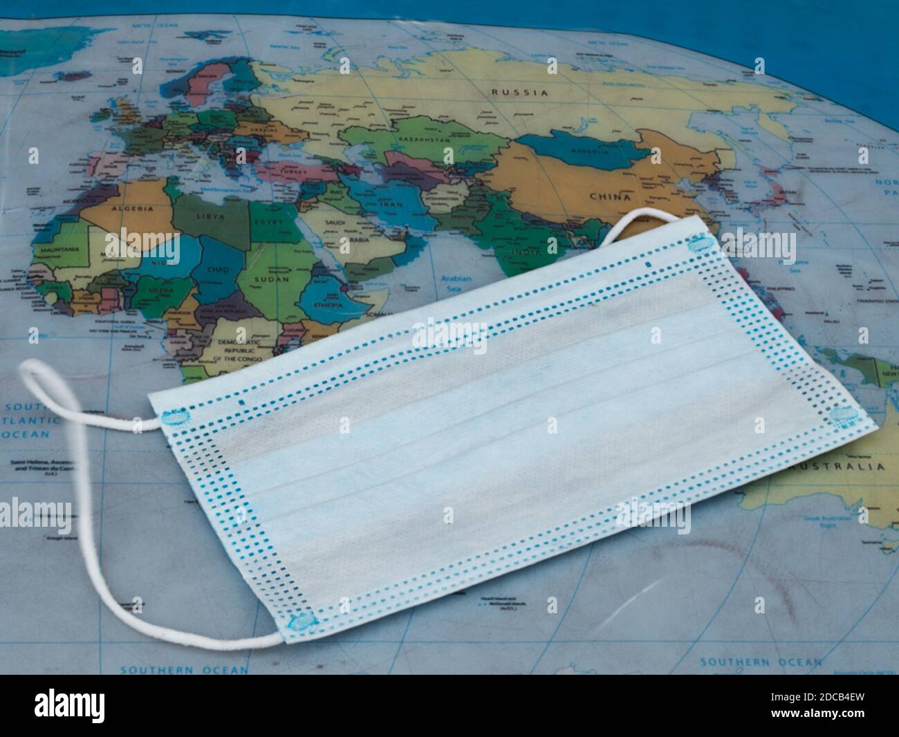 Side view of medical face mask on world map background. Prevent ...