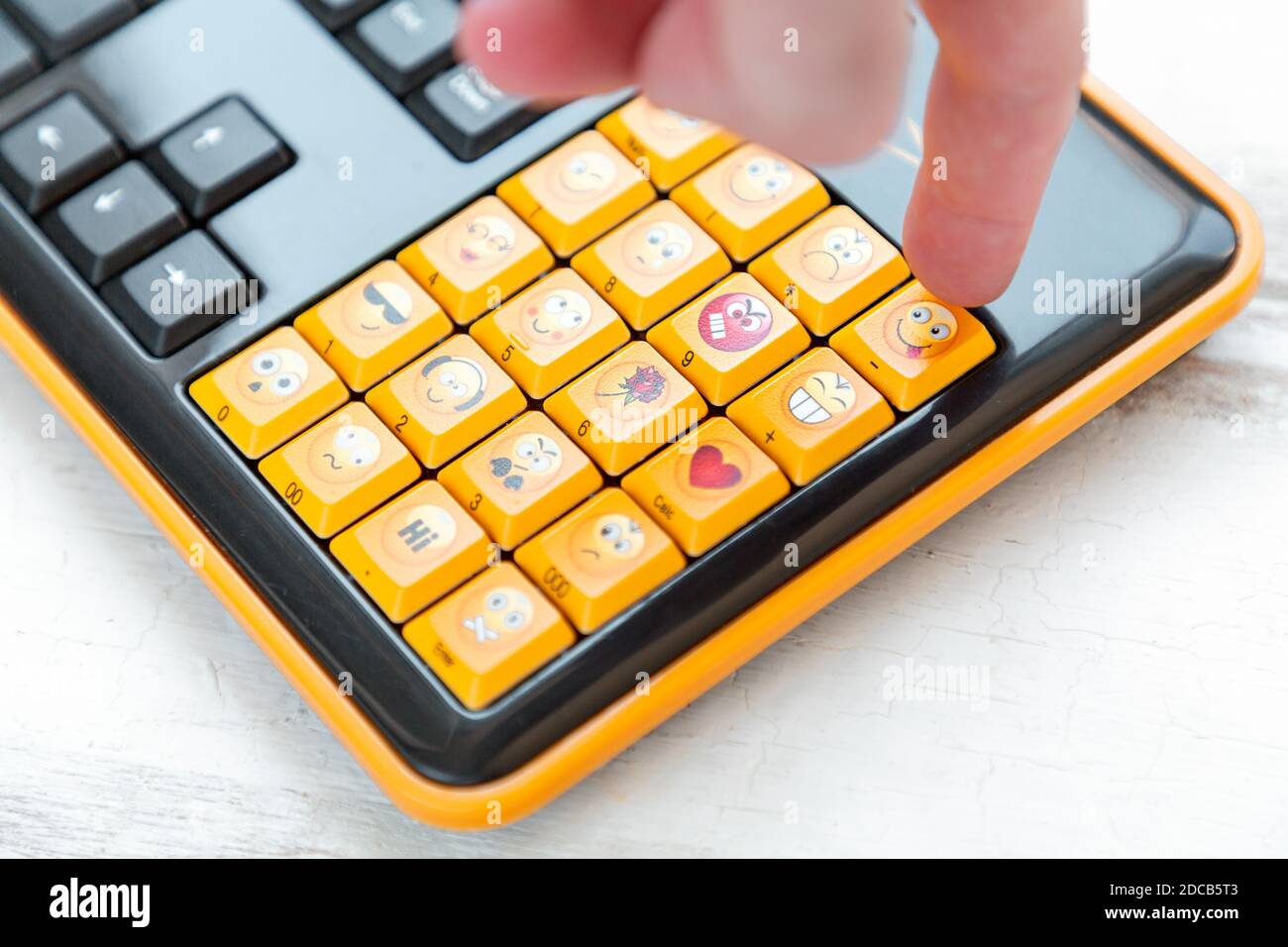 A hand presses a button with a happy smiley face on the keyboard ...