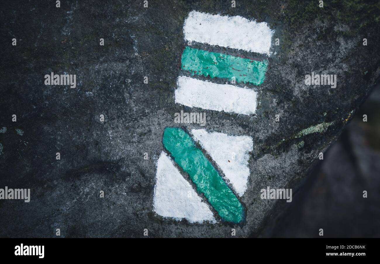 Hiking sign on a rock. A sign that lines a hiking trail. Green tourist ...