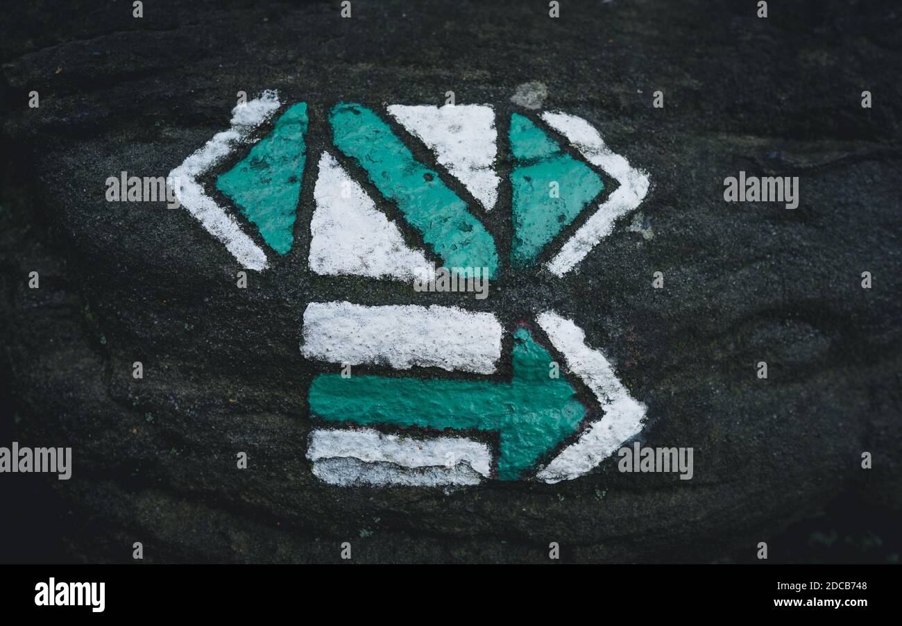 Hiking sign on a rock. A sign that lines a hiking trail. Green tourist ...