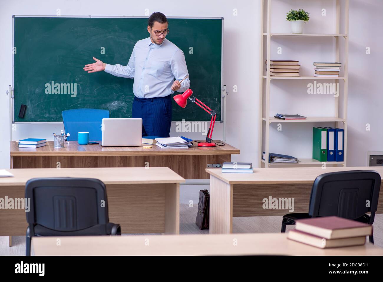 Young teacher in front of green board Stock Photo - Alamy