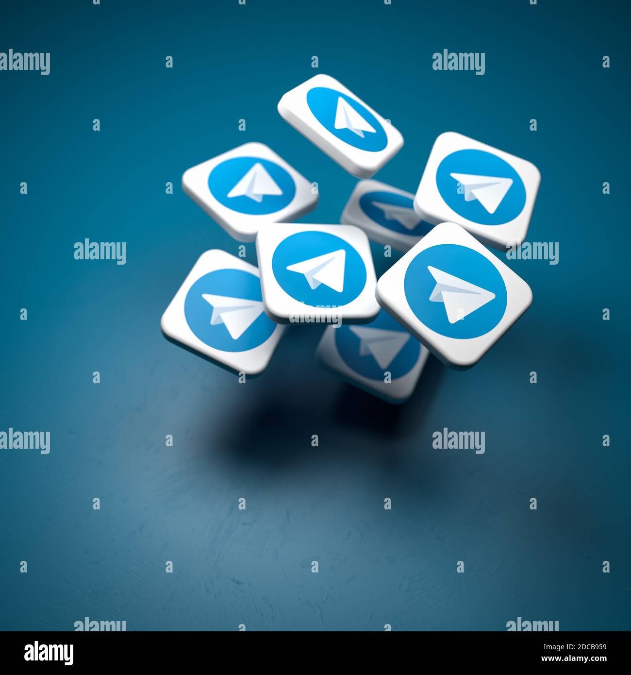 Logos of the messaging site and app Telegram falling onto a dark table ...