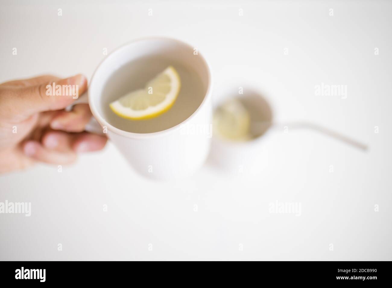 Hand holding a cup of lemon tea with a lemon slice inside Stock Photo ...