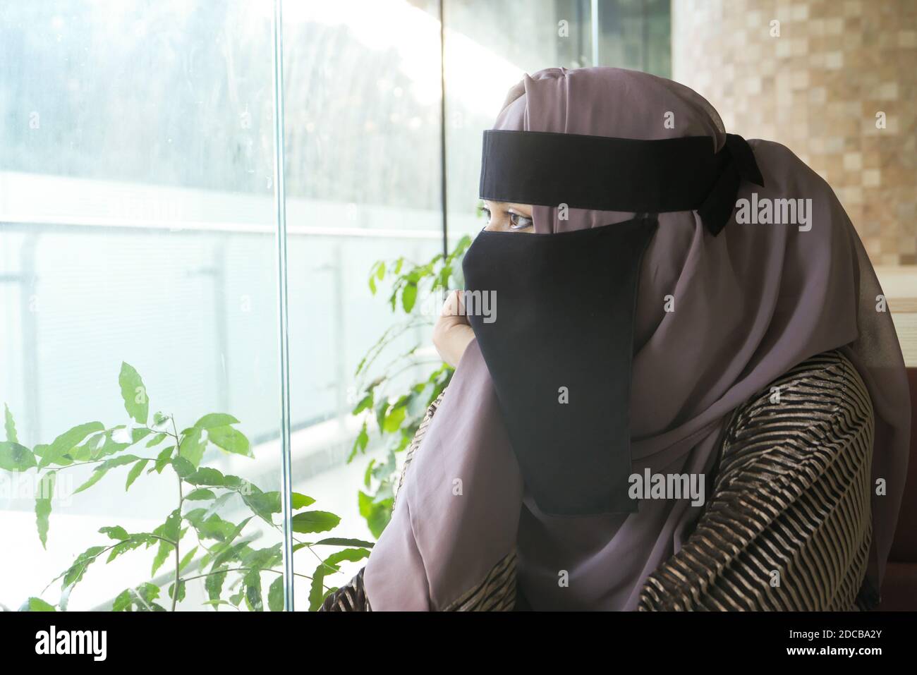 young muslim women covering face looking through window indoor Stock ...