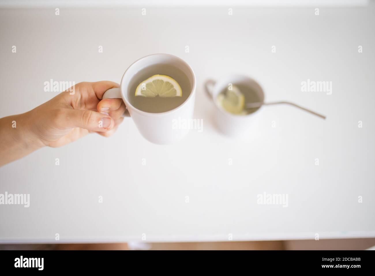 Hand holding a cup of lemon tea with a lemon slice inside Stock Photo ...