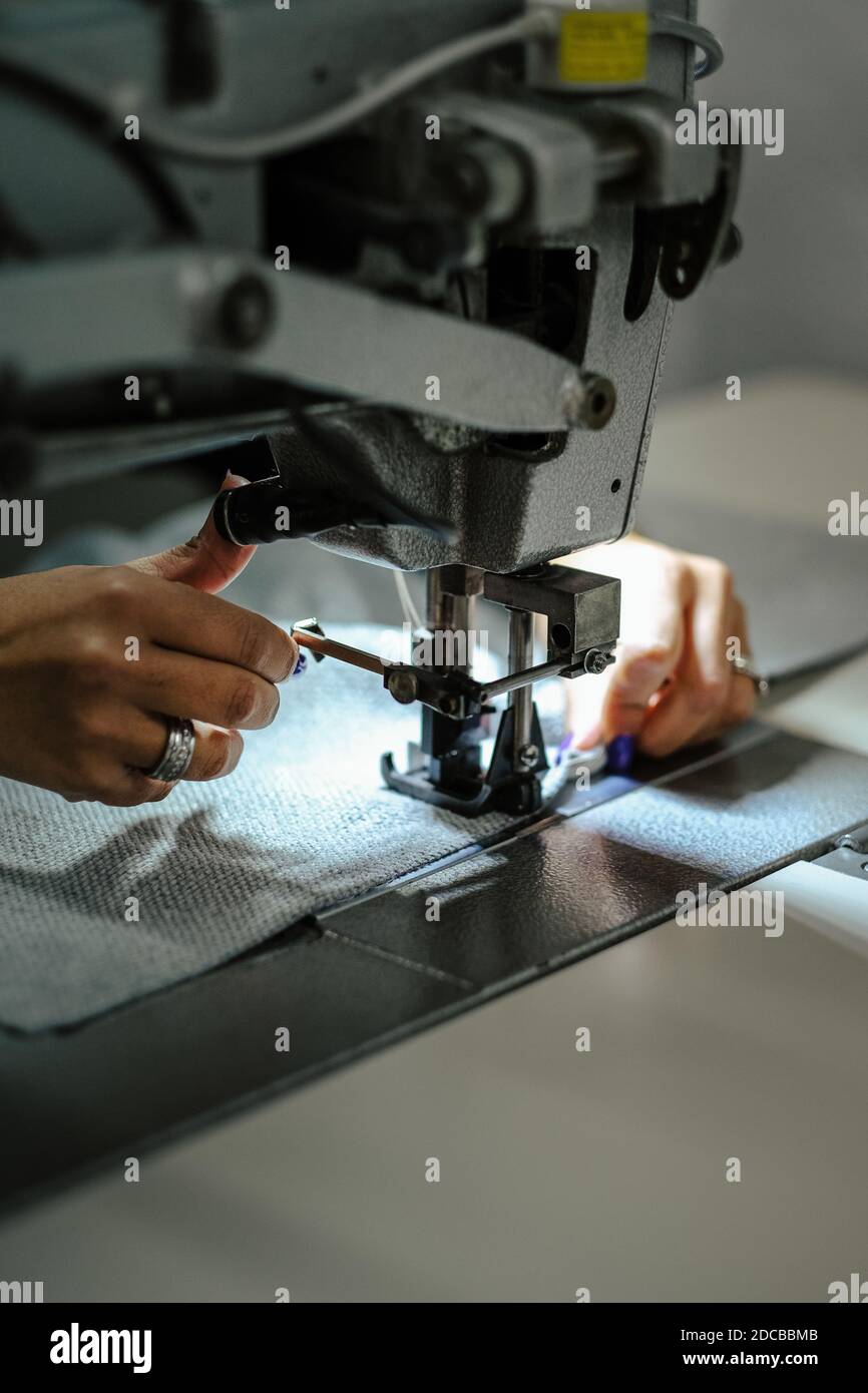 A vertical closeup shot of a female operating an industrial sewing ...