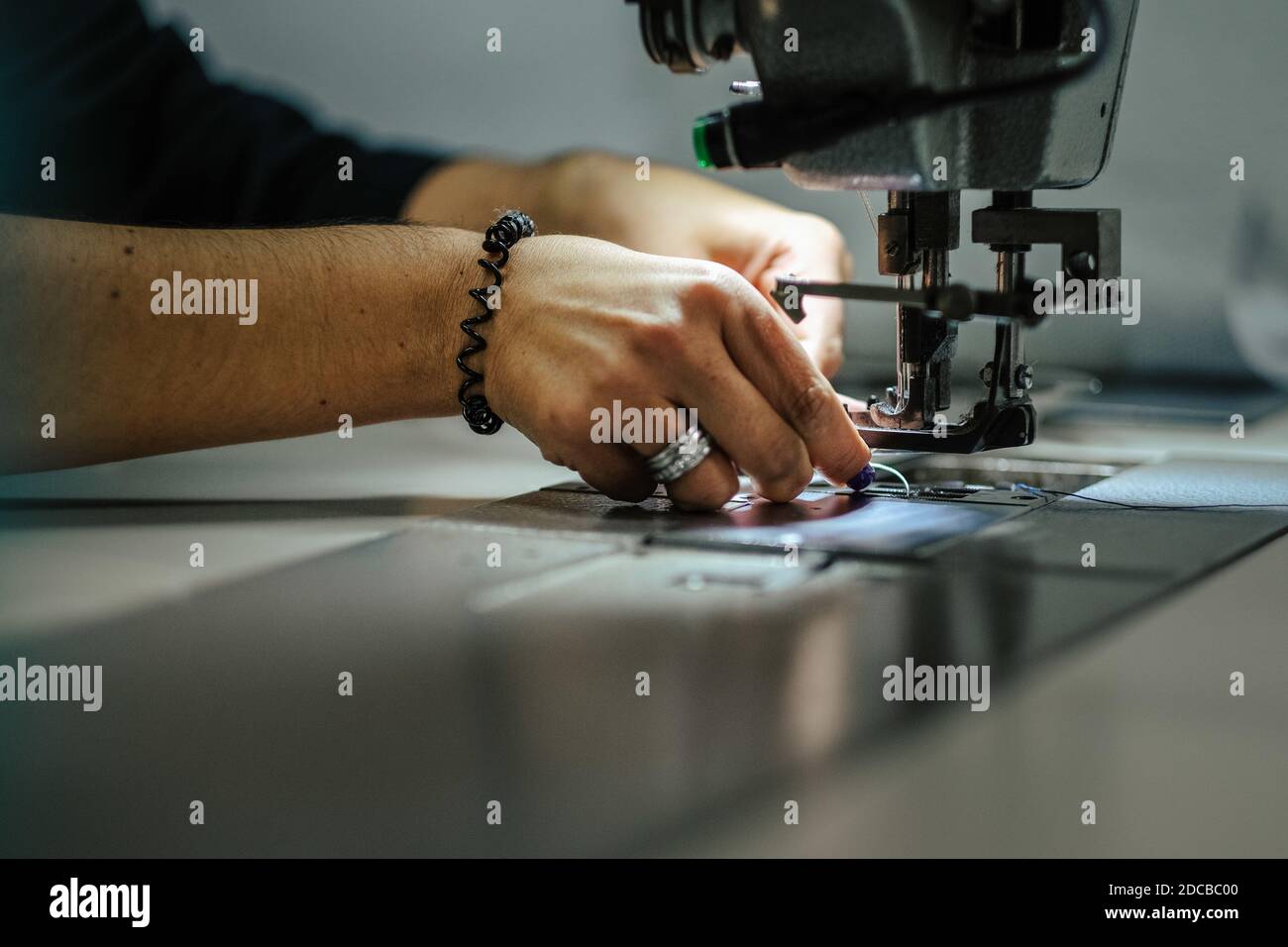 A closeup shot of female hands operating an industrial sewing machine ...