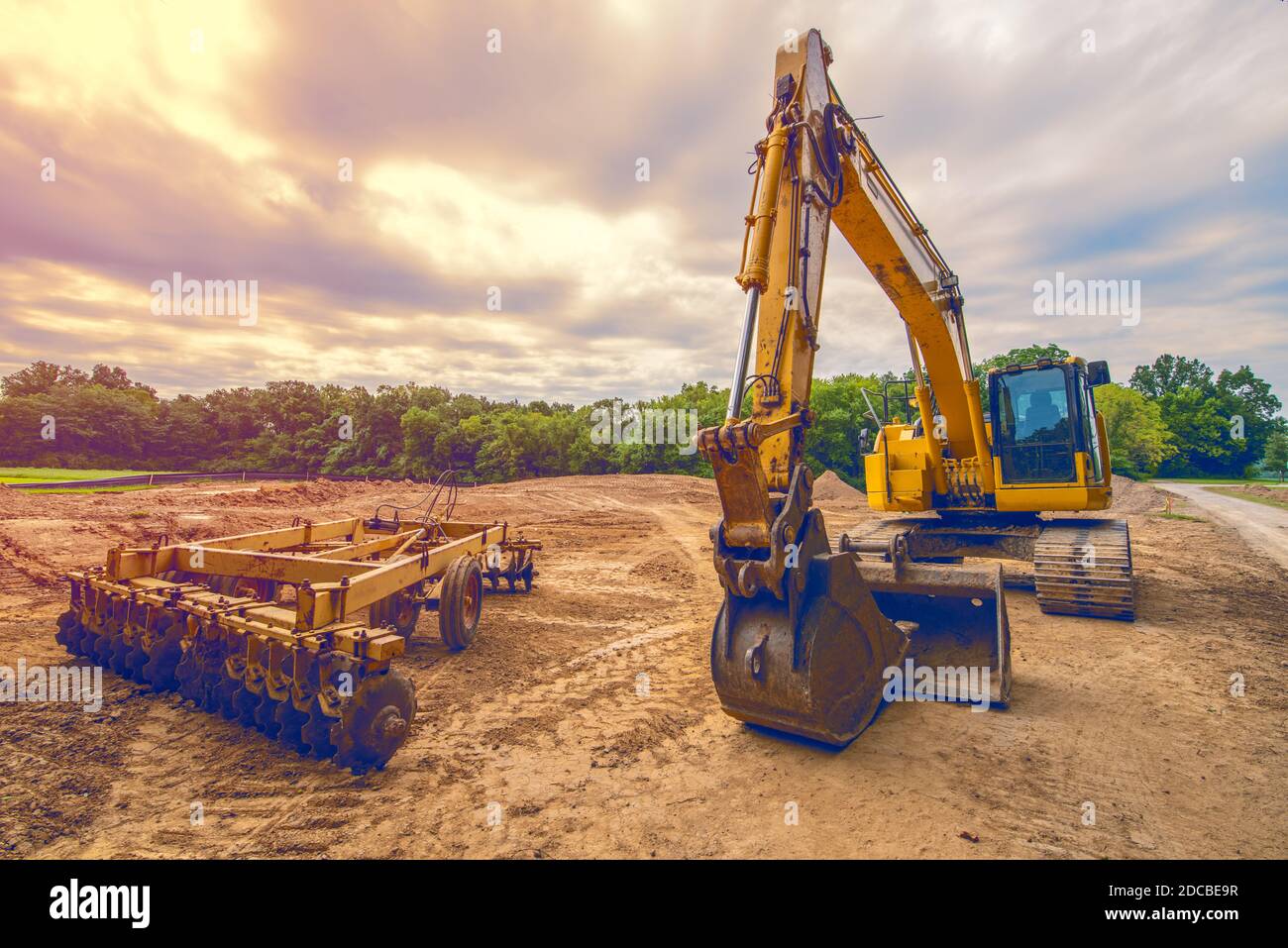 Yellow construction backhoe and disk plow heavy equipment sit in open ...