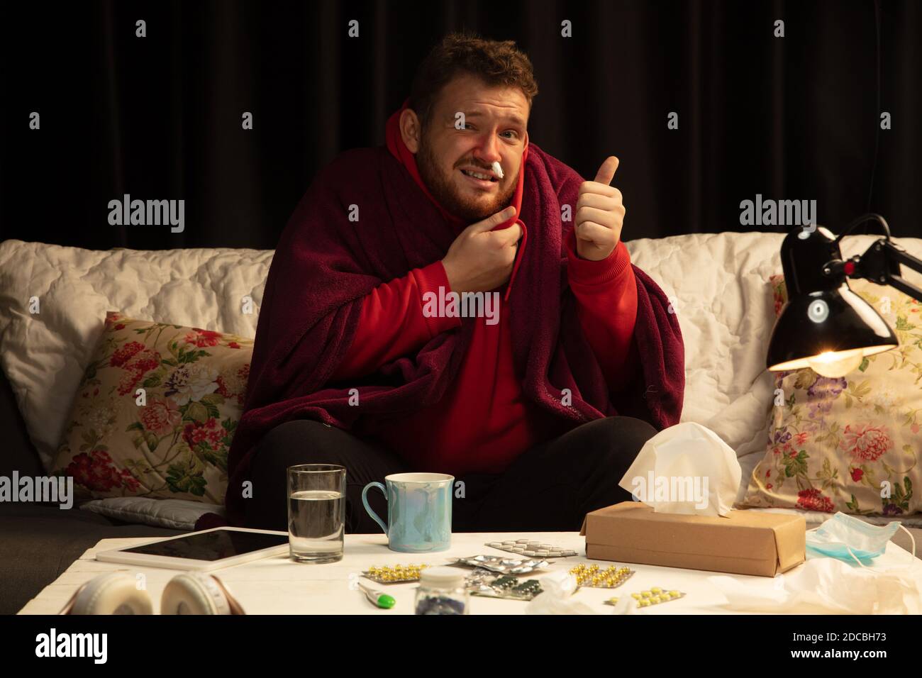 Rainy nose. Young man wrapped in a plaid looks sick, ill, sneezing and ...