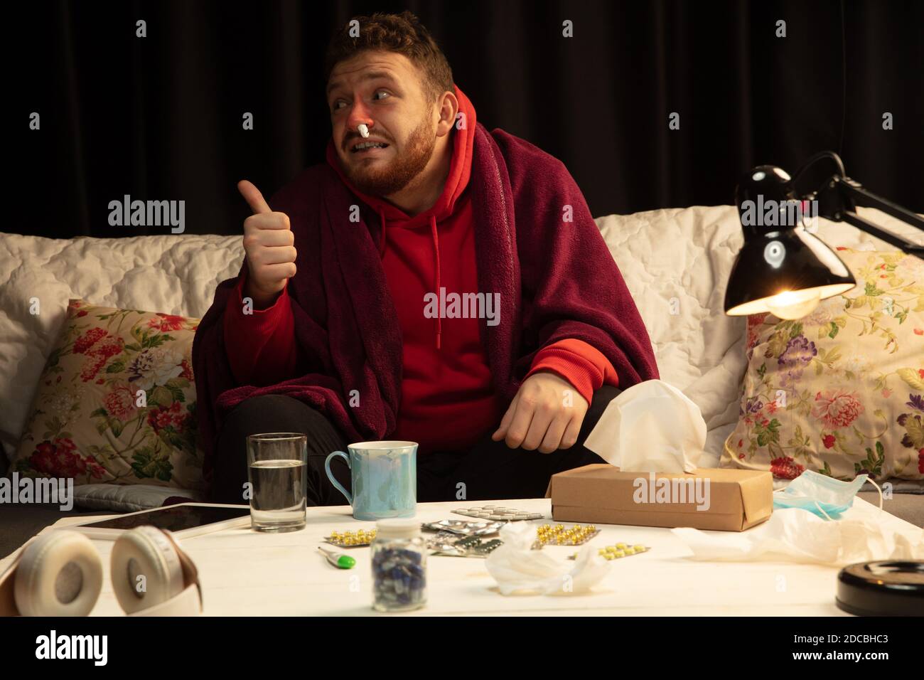 Rainy nose. Young man wrapped in a plaid looks sick, ill, sneezing and ...