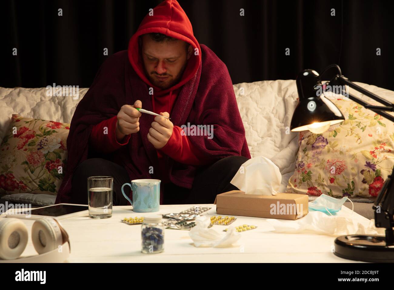 Fever. Young man wrapped in a plaid looks sick, ill, sneezing and ...